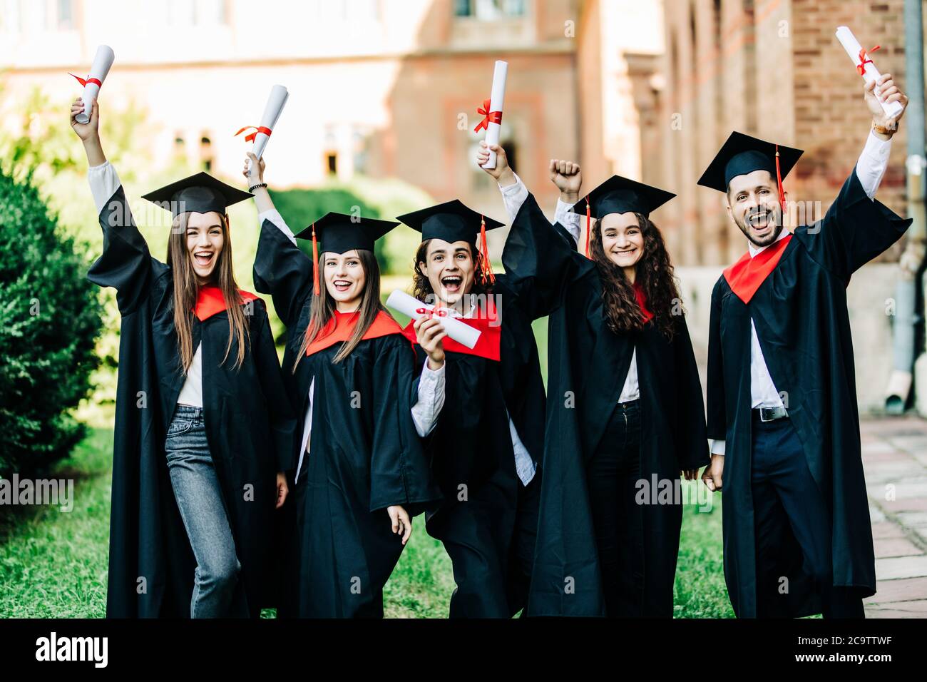 Happy graduates. Five college graduates standing in a row and smiling ...