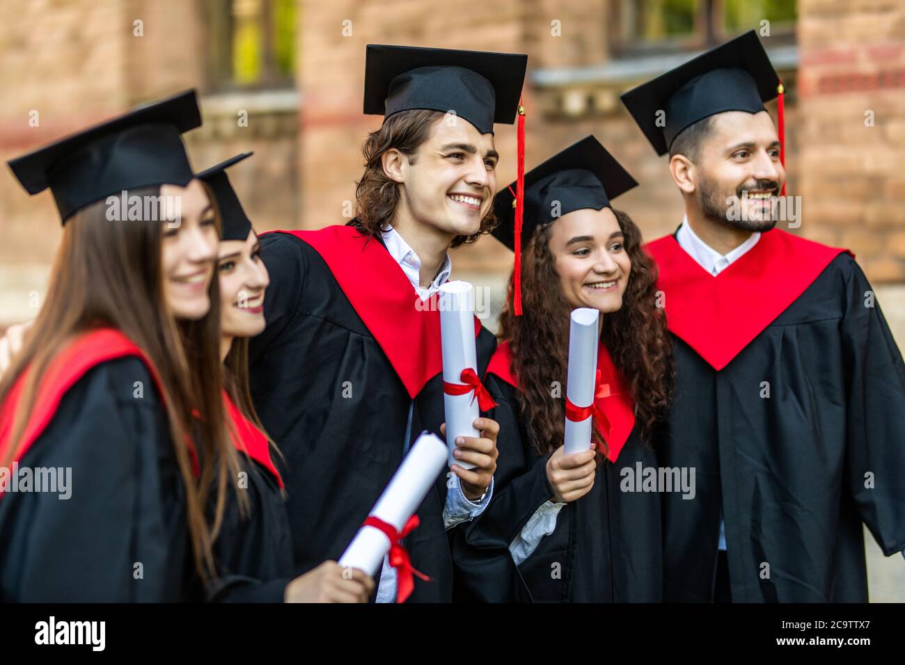 Graduates embrace, enjoy and look at the camera on the graduation ...