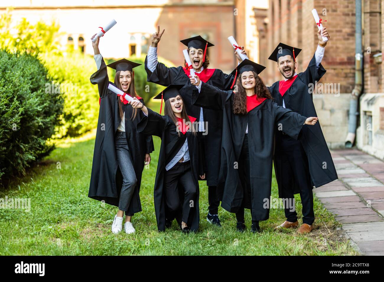 Happy graduates. Five college graduates standing in a row and smiling ...
