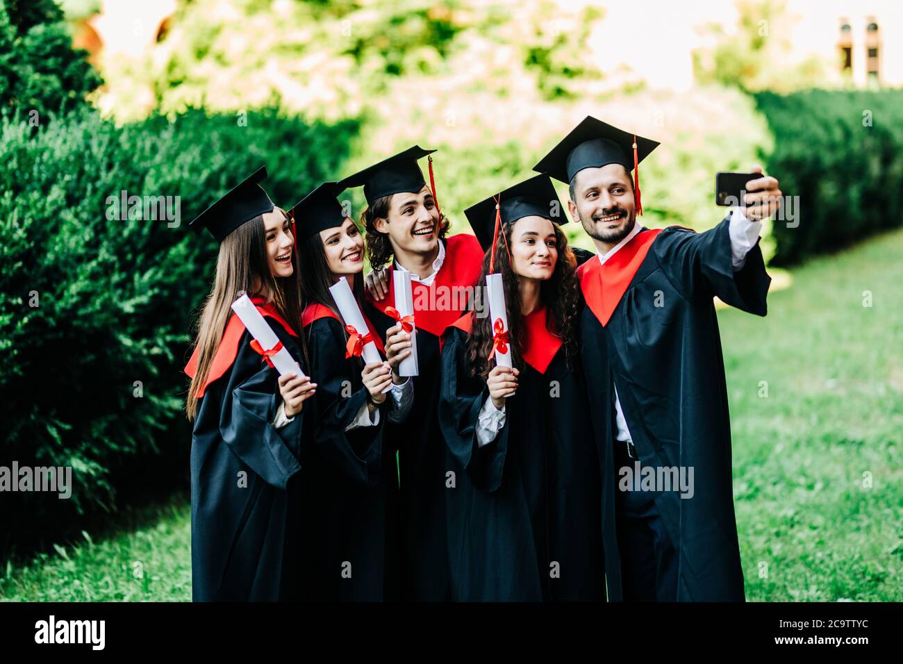 excited five successful happy five graduates in robes and hats with ...