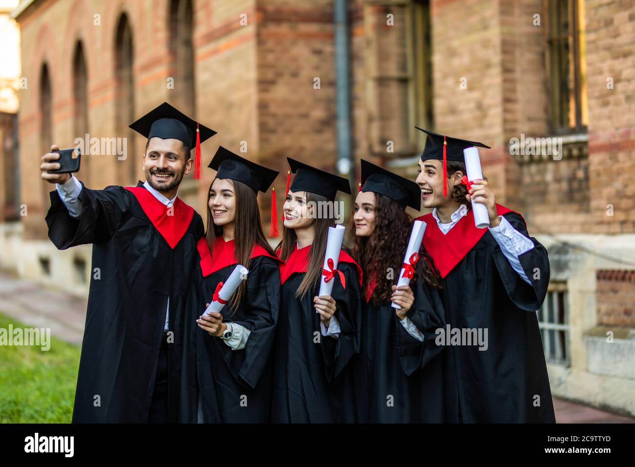 excited five successful happy five graduates in robes and hats with ...