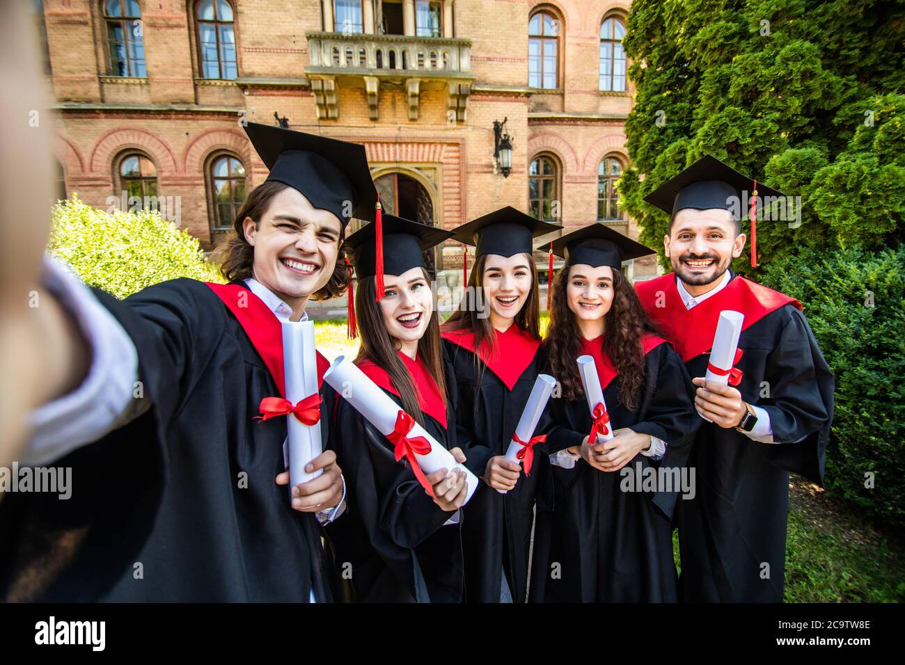 excited five successful happy five graduates in robes and hats with ...