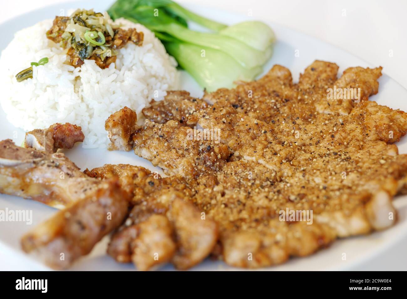 Taiwanese Slice Pork Chop with rice and Pak Choi serve on white plate ...