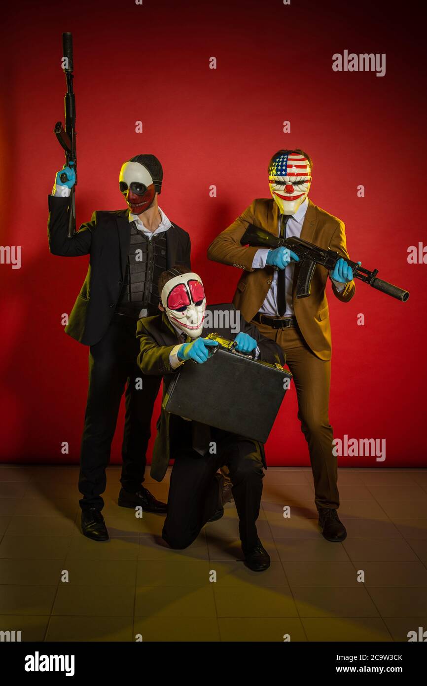 Actor man in a mask with a weapon in his hands posing on a red ...
