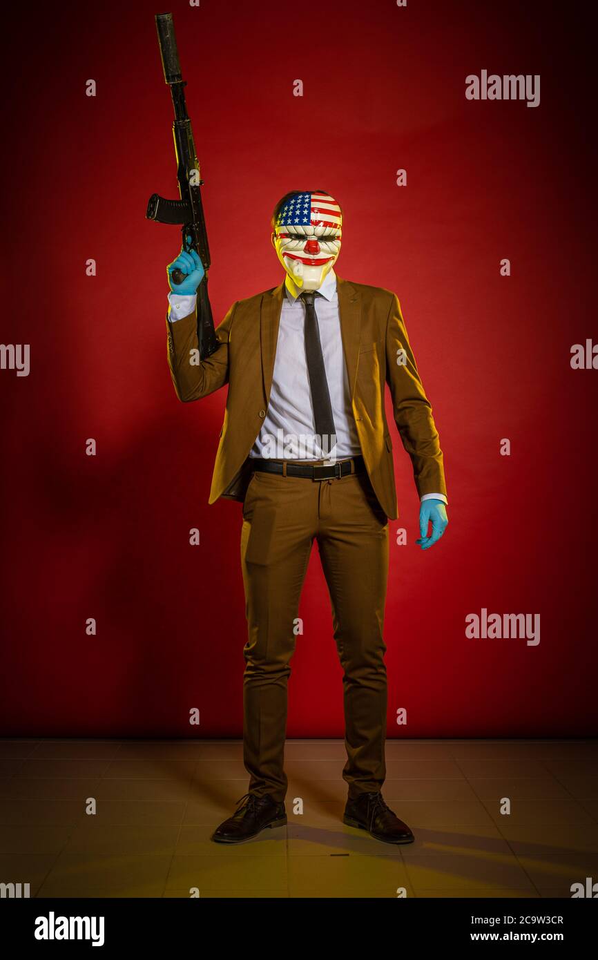 Actor man in a mask with a weapon in his hands posing on a red ...