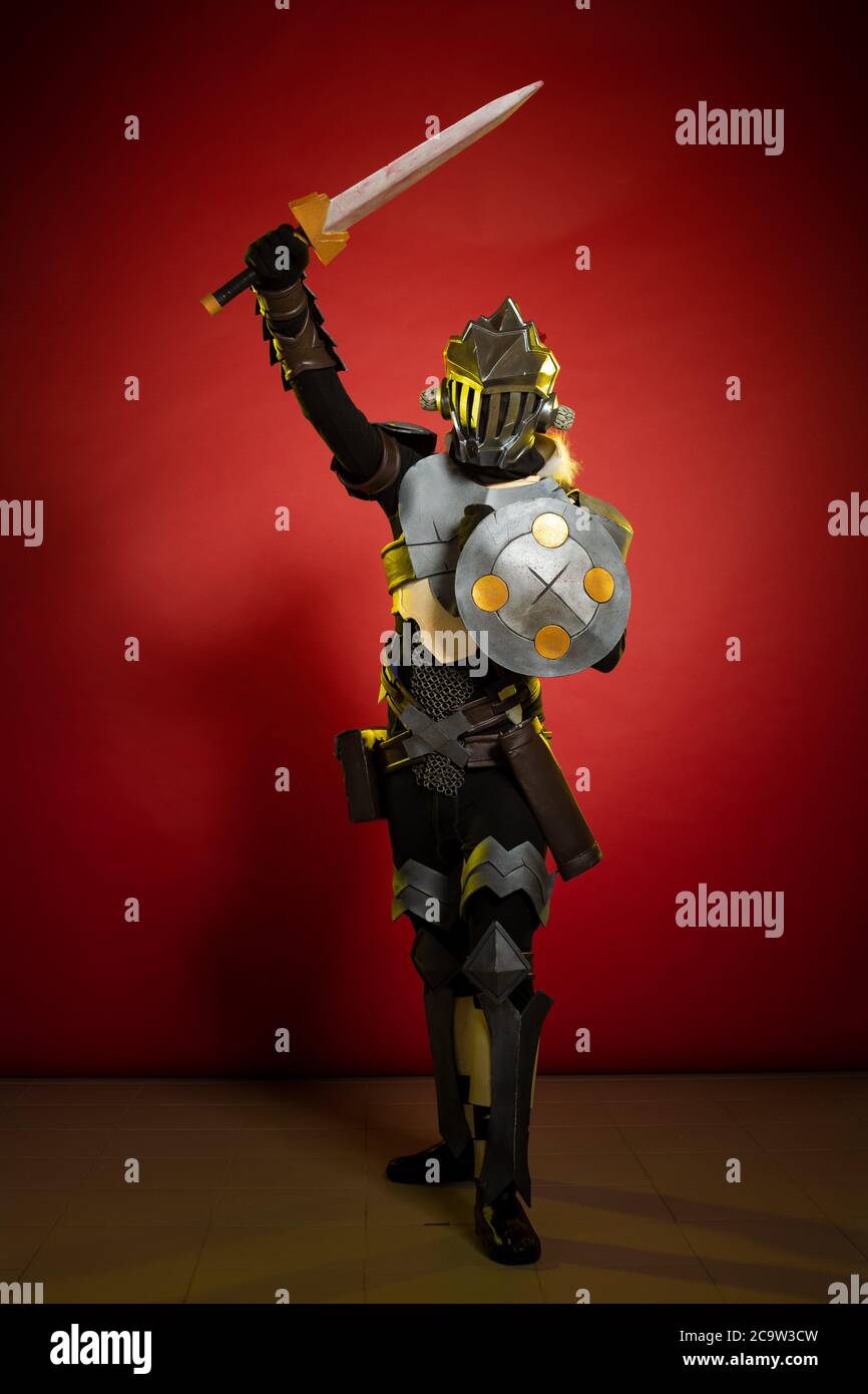 Actor man in a helmet and armor of a knight posing on a red background ...