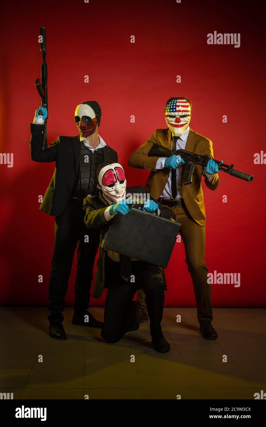 Actor man in a mask with a weapon in his hands posing on a red ...