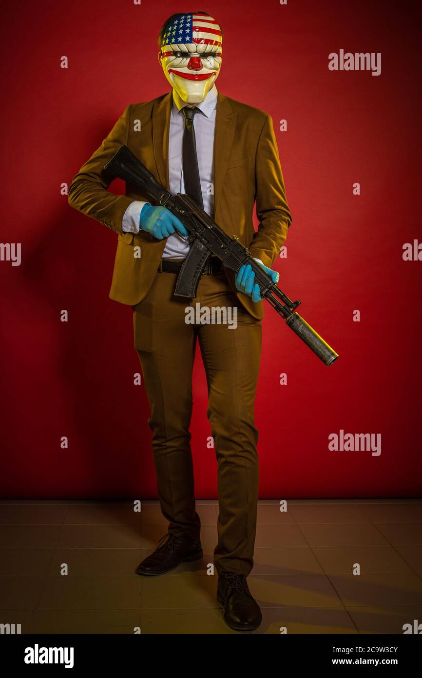 Actor man in a mask with a weapon in his hands posing on a red ...