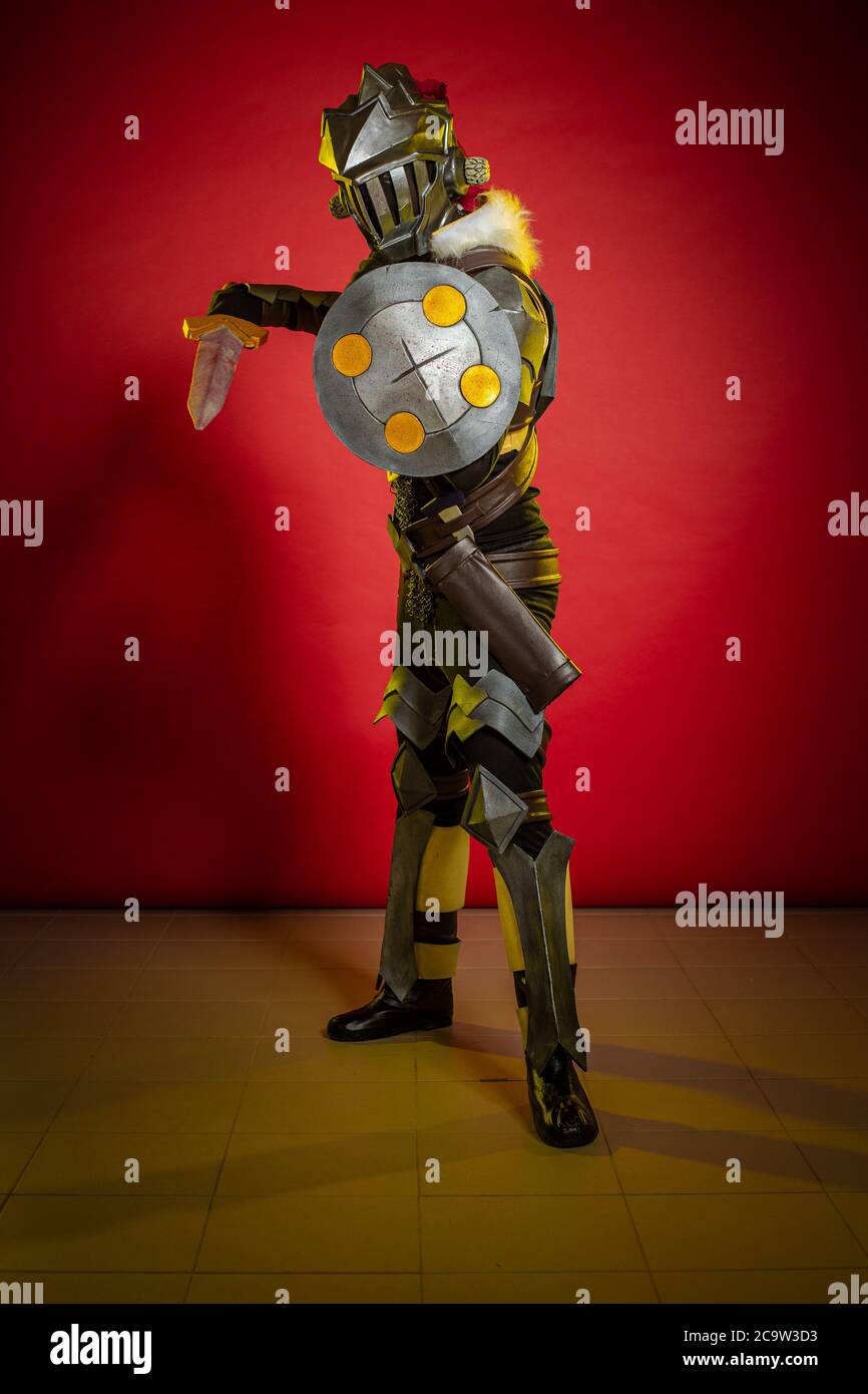 Actor man in a helmet and armor of a knight posing on a red background ...
