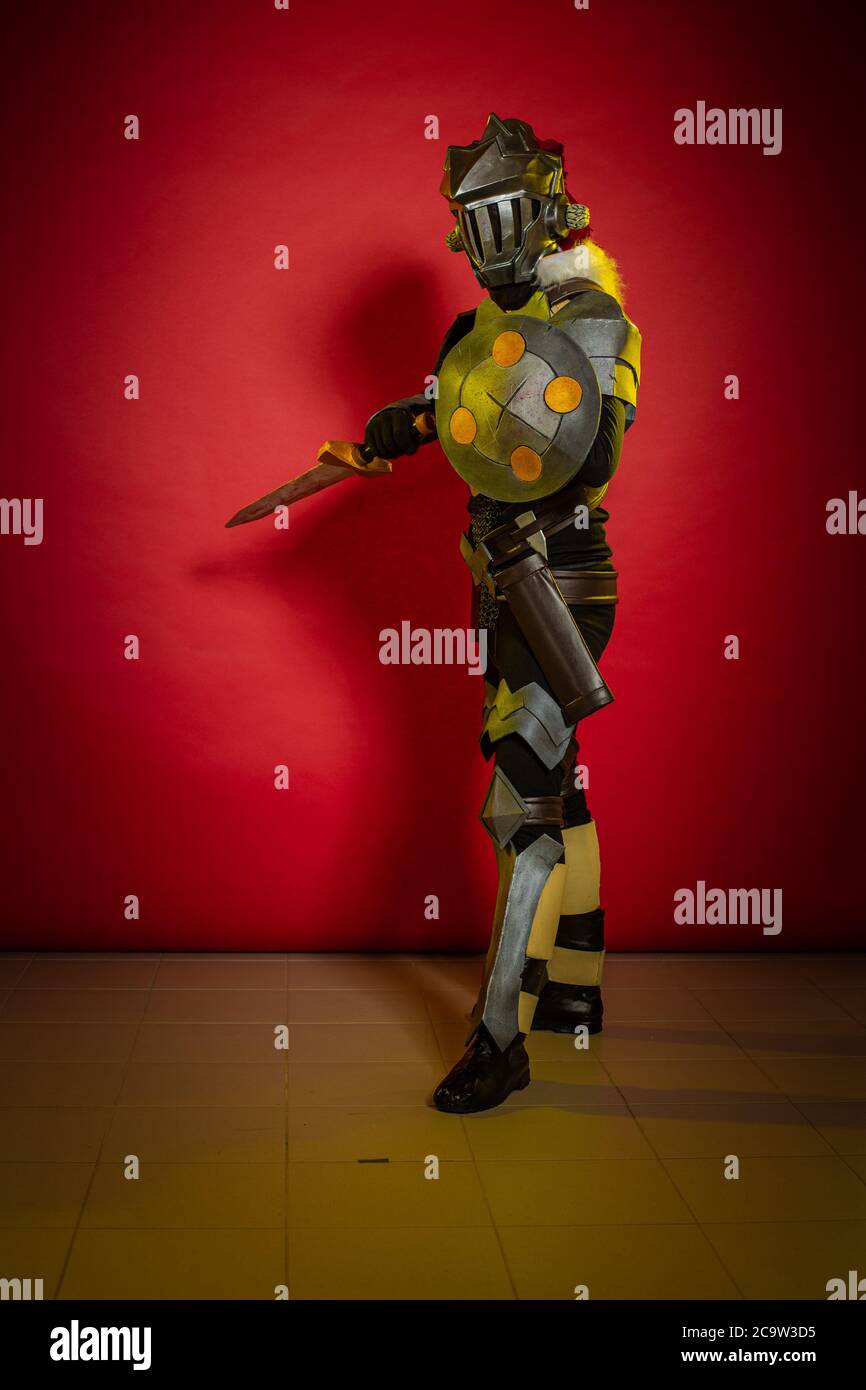 Actor man in a helmet and armor of a knight posing on a red background ...
