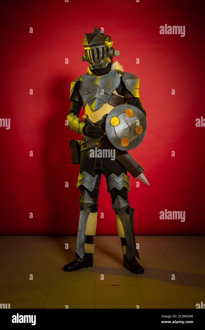 Actor man in a helmet and armor of a knight posing on a red background ...