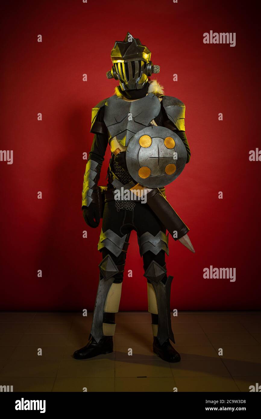 Actor man in a helmet and armor of a knight posing on a red background ...