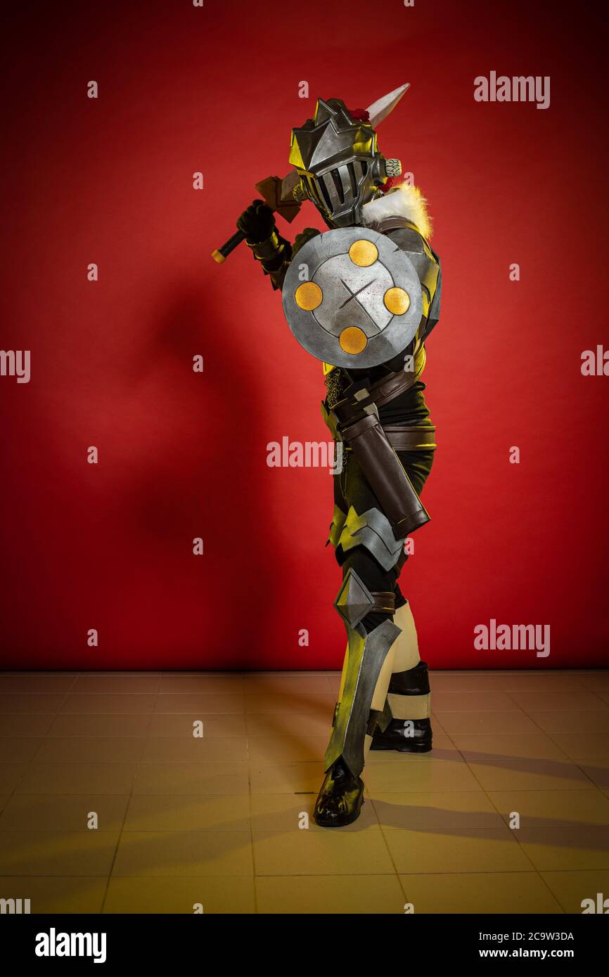 Actor man in a helmet and armor of a knight posing on a red background ...