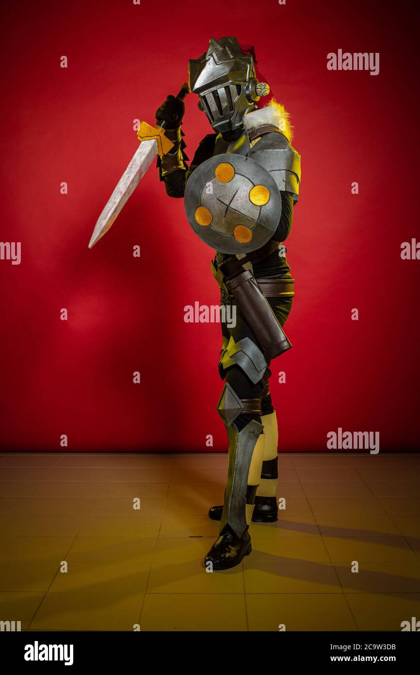 Actor man in a helmet and armor of a knight posing on a red background ...