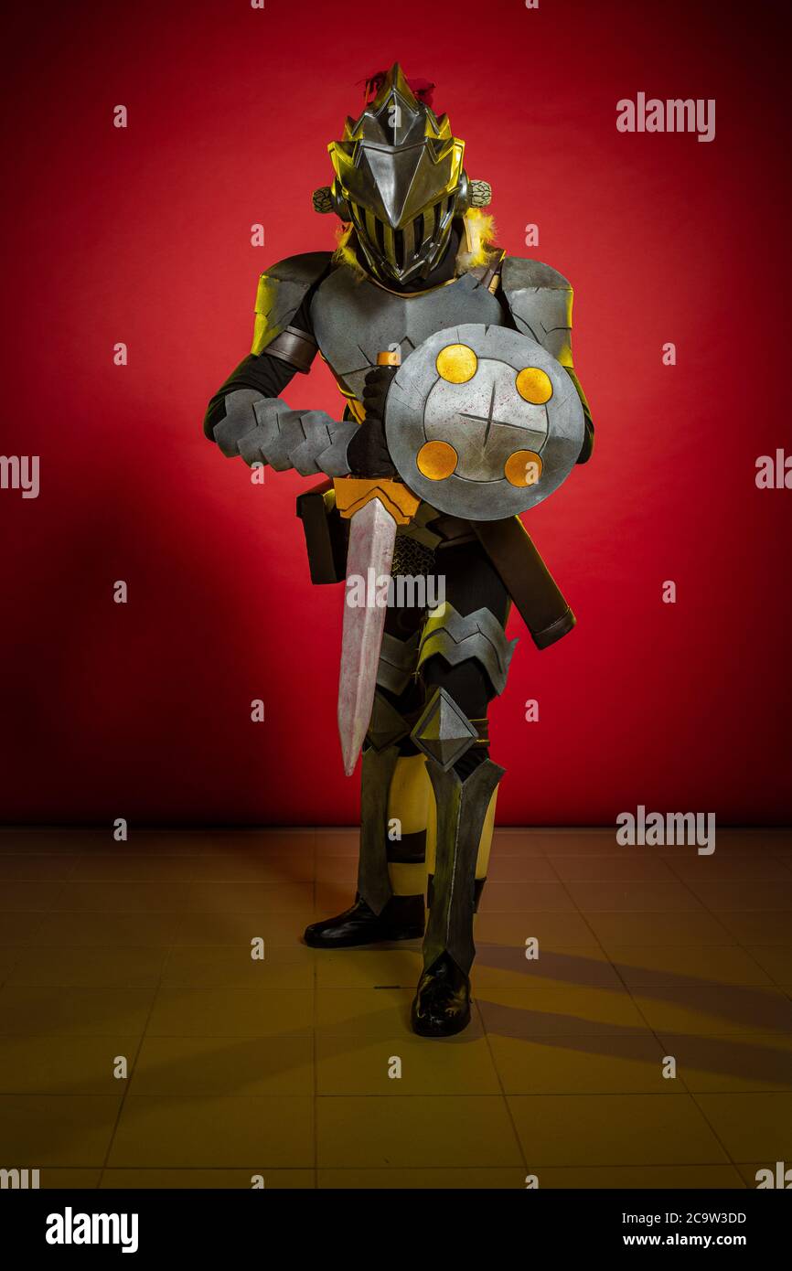 Actor man in a helmet and armor of a knight posing on a red background ...