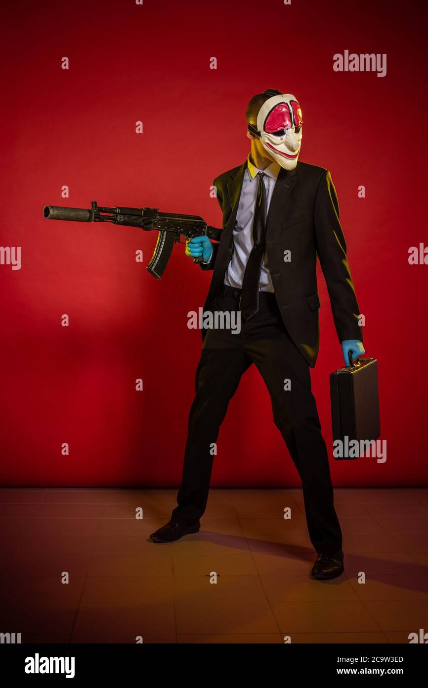 Actor man in a mask with a weapon in his hands posing on a red ...