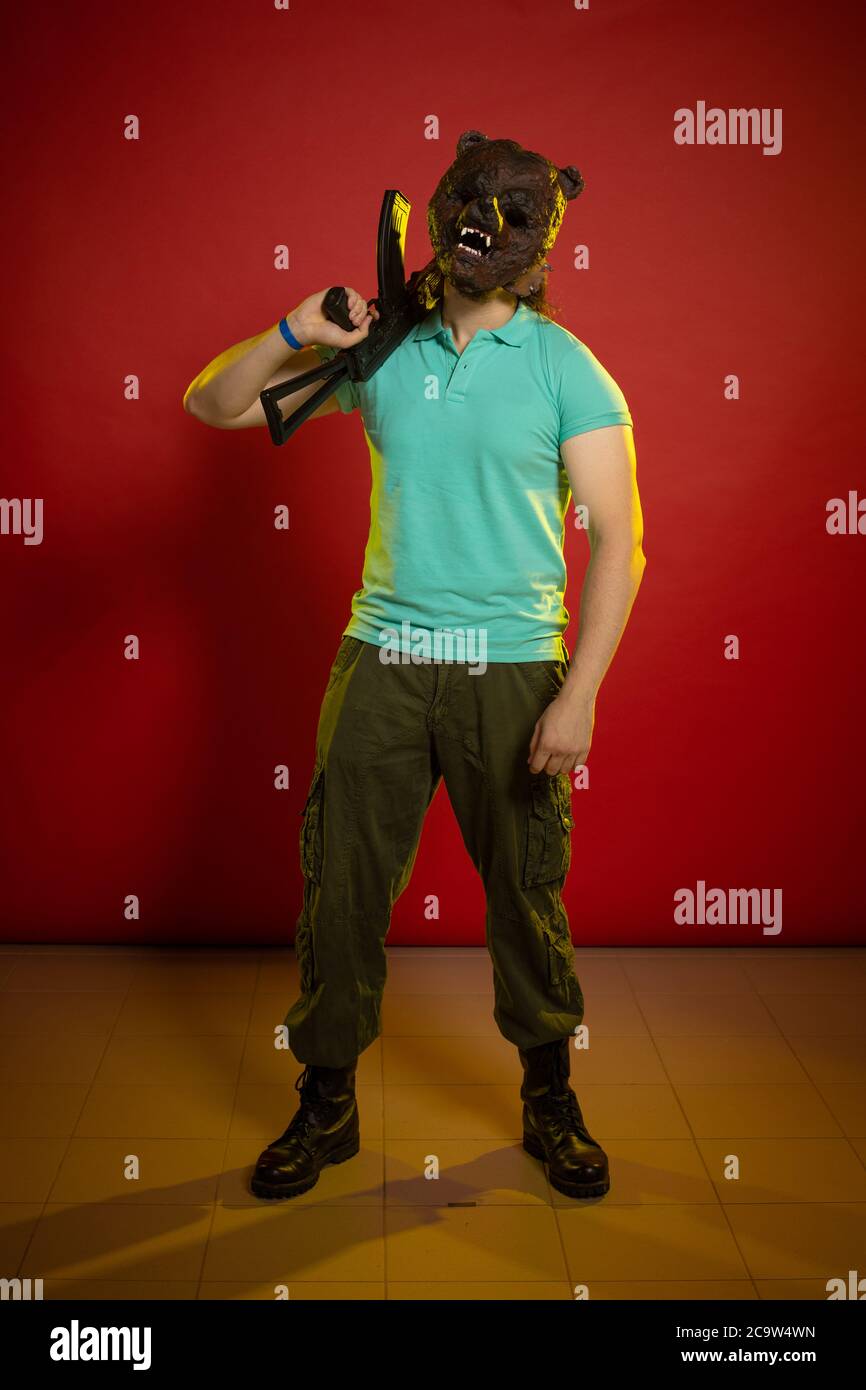 Actor man in a mask with a weapon in his hands posing on a red ...