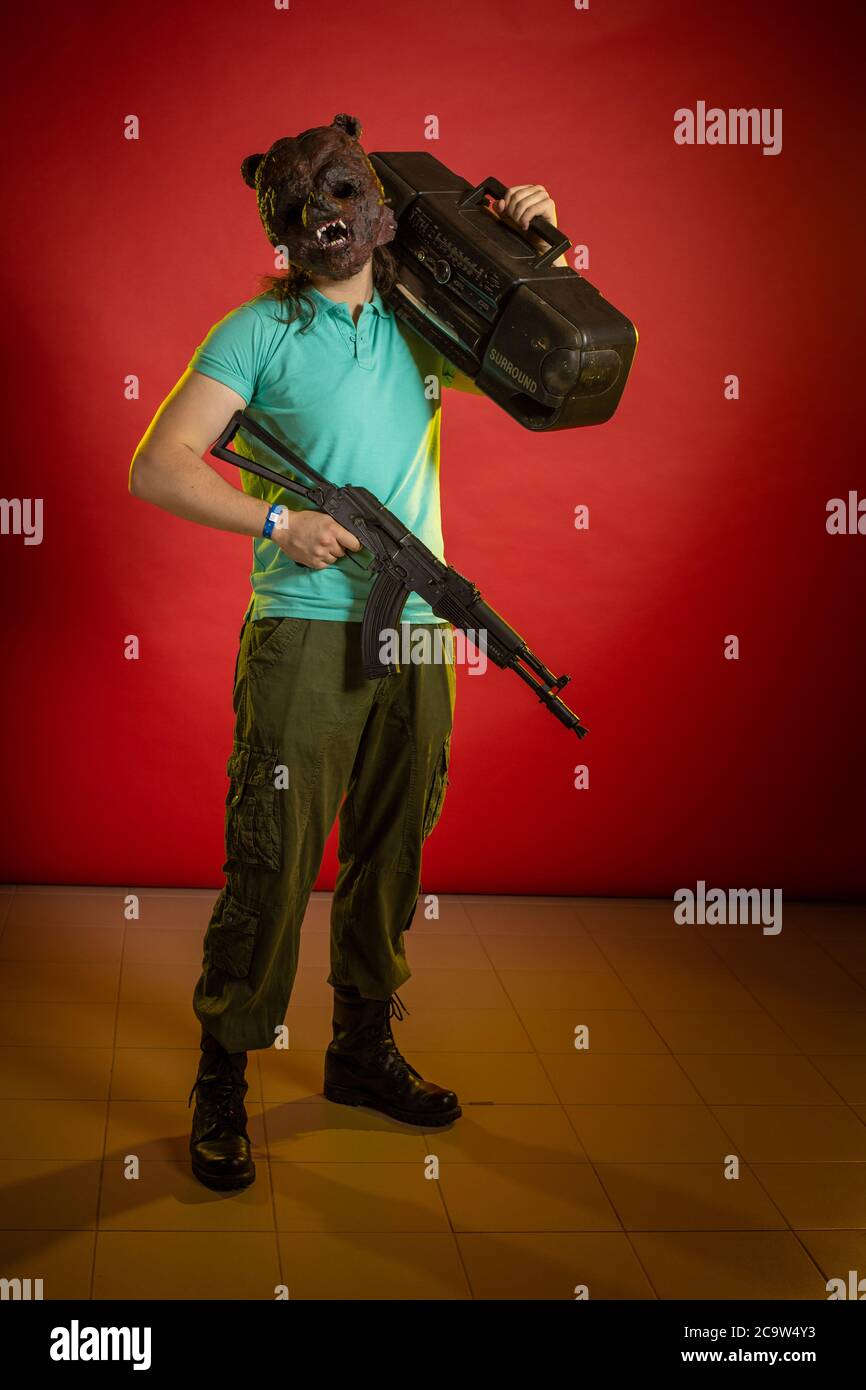 Actor man in a mask with a weapon in his hands posing on a red ...