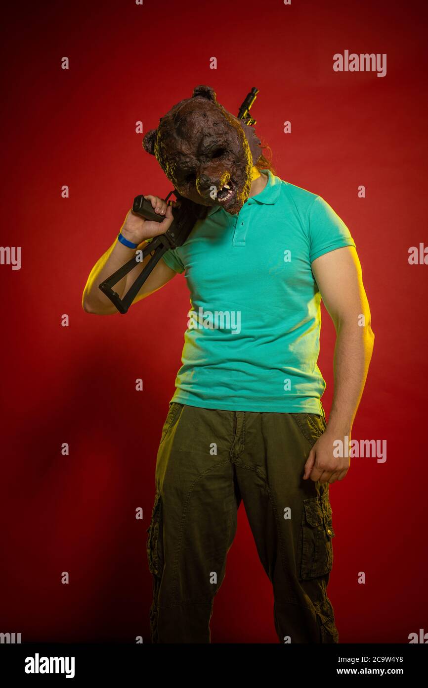 Actor man in a mask with a weapon in his hands posing on a red ...