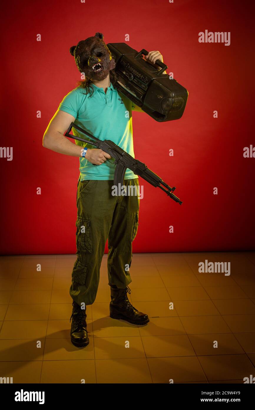Actor man in a mask with a weapon in his hands posing on a red ...