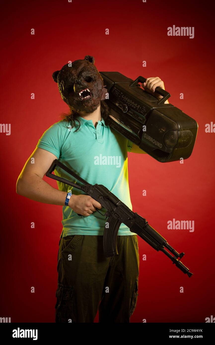 Actor man in a mask with a weapon in his hands posing on a red ...