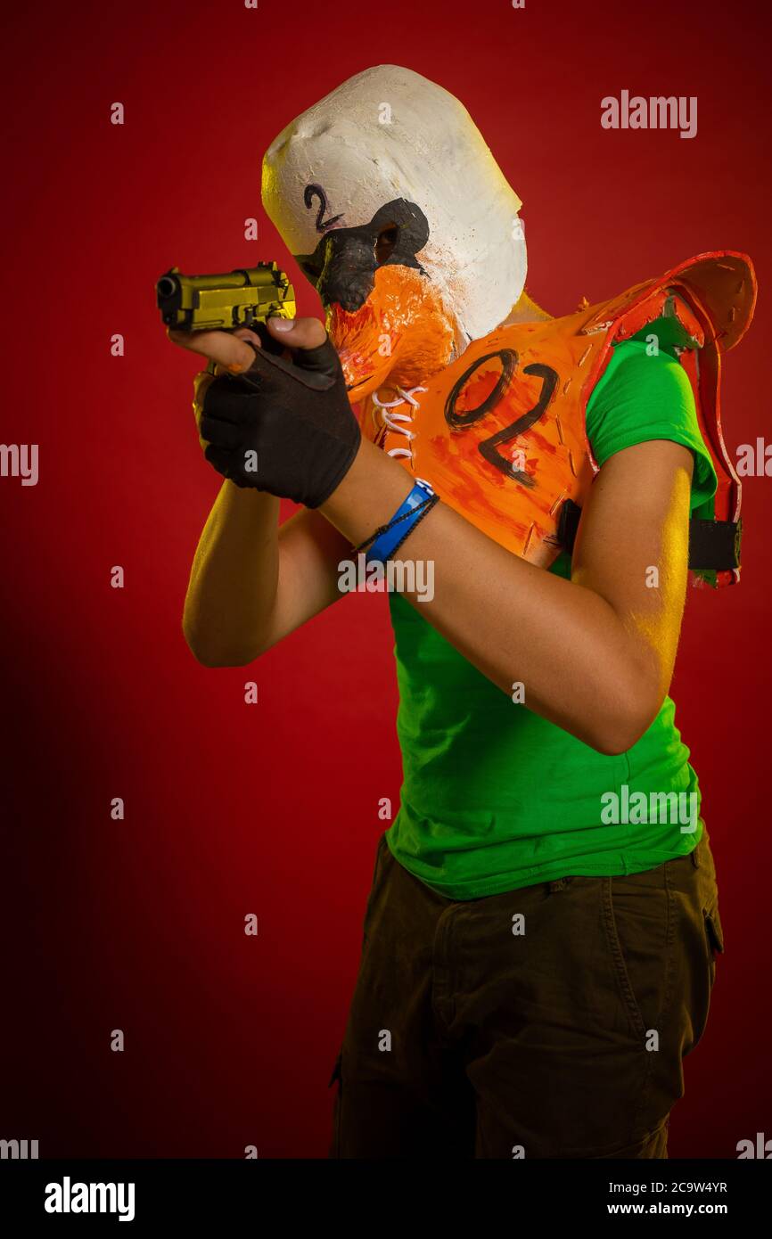 Actor man in a mask with a weapon in his hands posing on a red ...