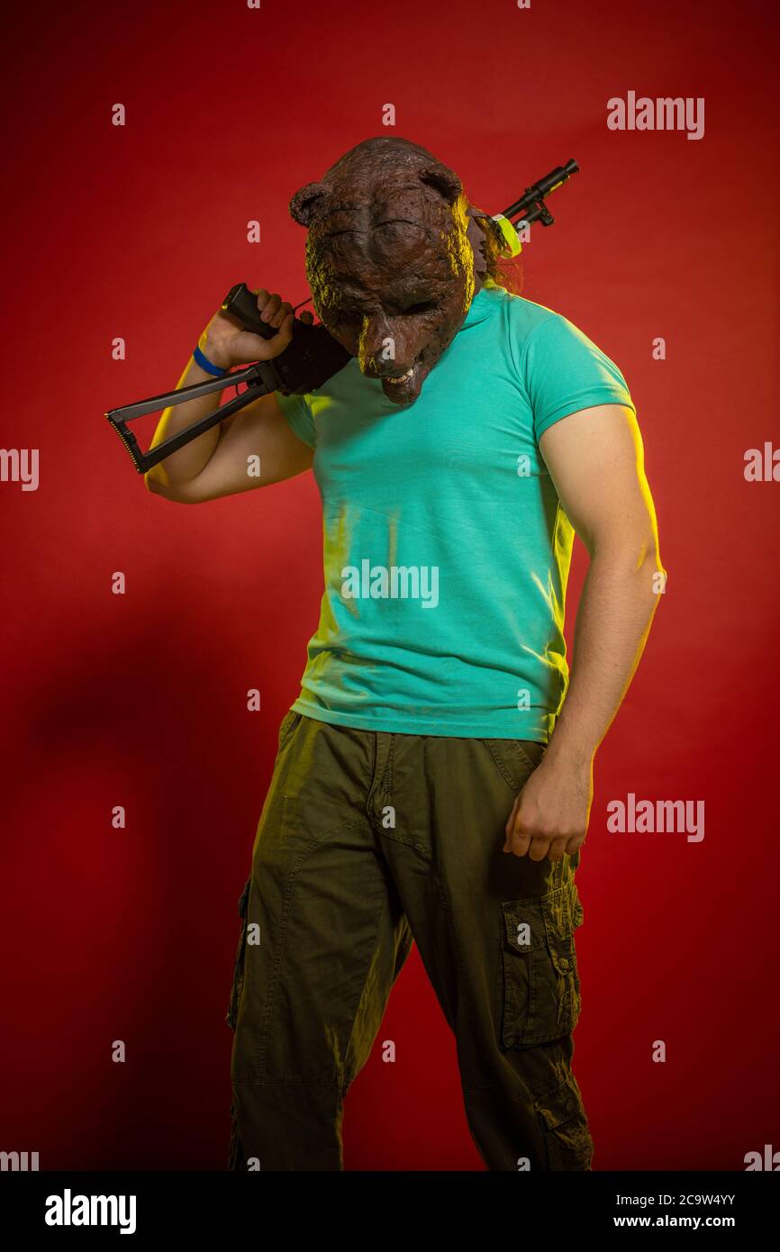Actor man in a mask with a weapon in his hands posing on a red ...