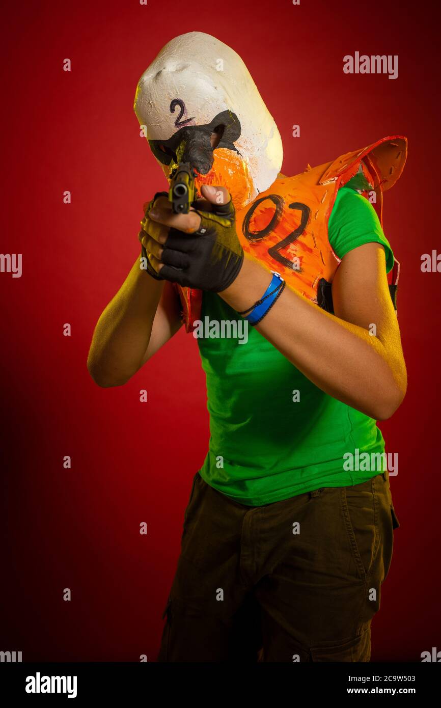Actor man in a mask with a weapon in his hands posing on a red ...