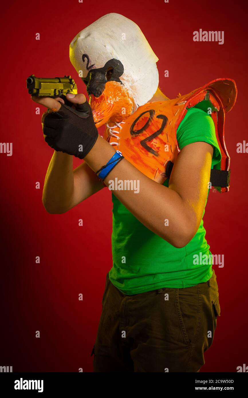 Actor man in a mask with a weapon in his hands posing on a red ...
