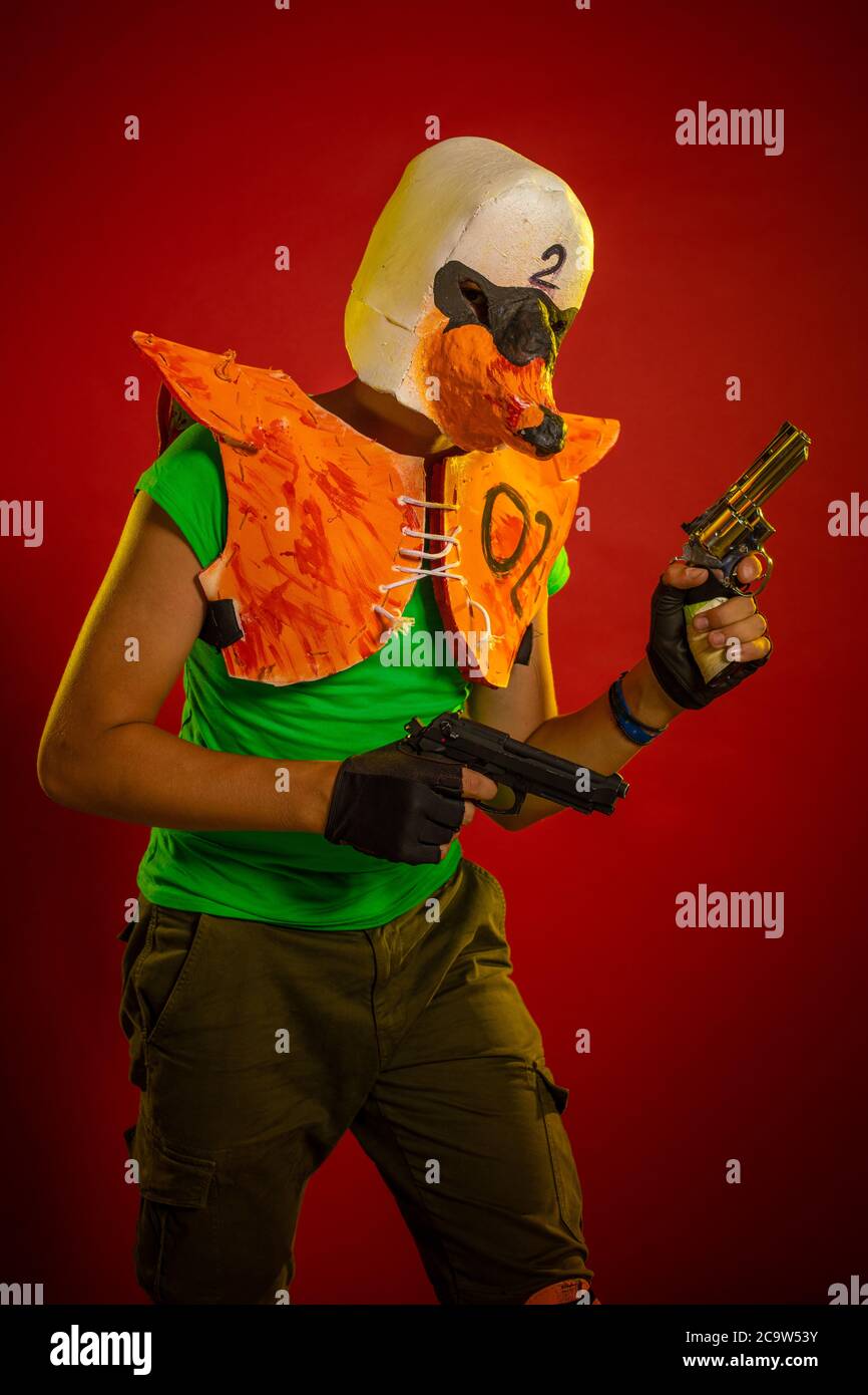 Actor man in a mask with a weapon in his hands posing on a red ...