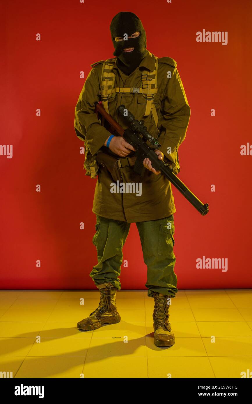 Actor man in a military helmet, mask and uniform posing on a red ...