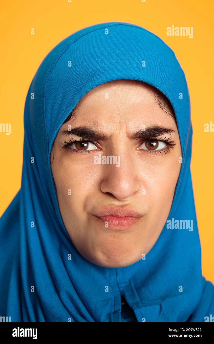 Uncertain. Close up young muslim woman isolated on yellow studio ...