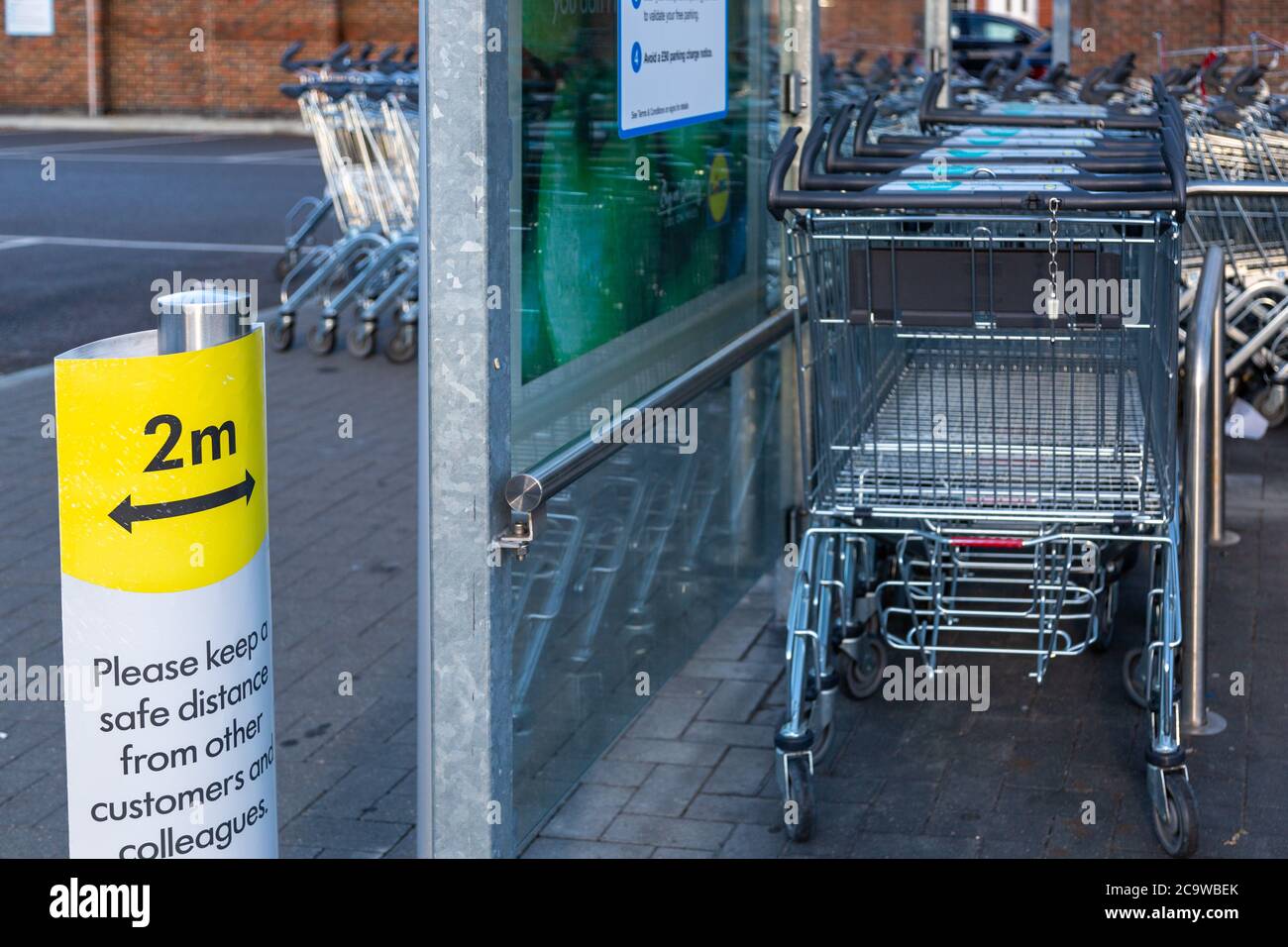 A two meter distancing sign next to trolleys in a supermarket trolley ...