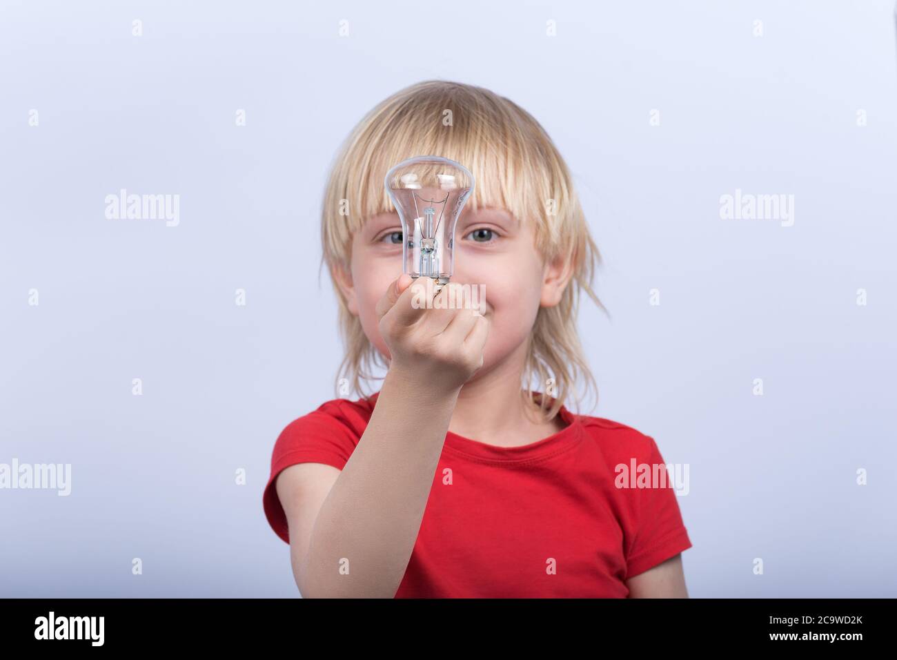 Blond boy holding light bulb. Portrait of child with bulb in hand on ...
