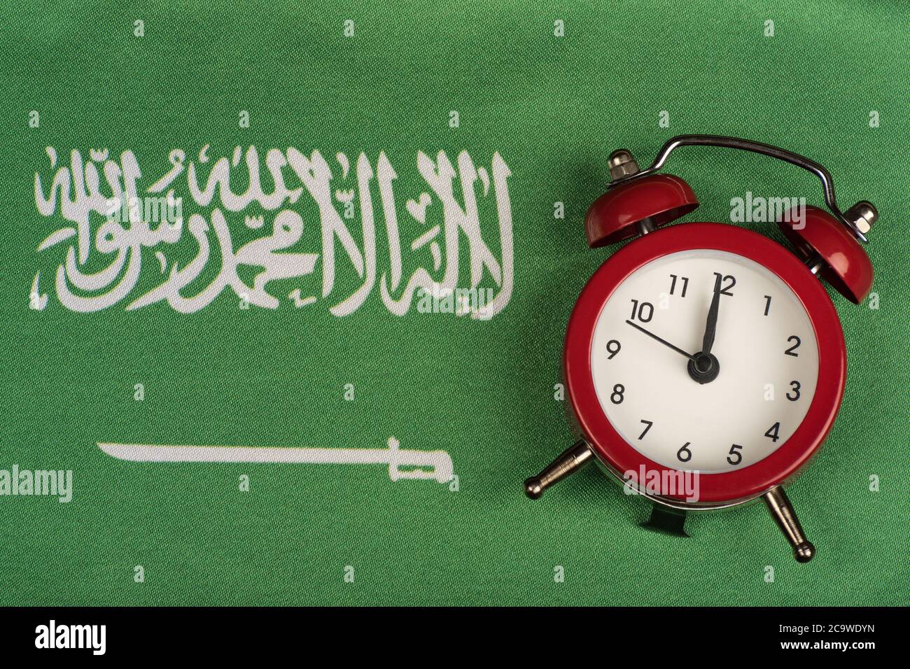 Saudi Arabia flag and vintage alarm clock close up. Green flag with ...