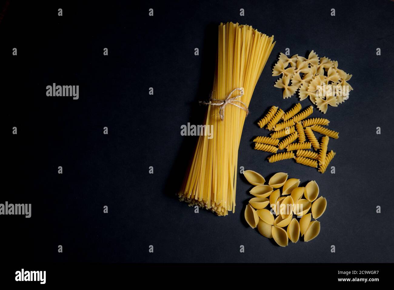 Assorted types of pasta on black background. Top view. Various forms of ...