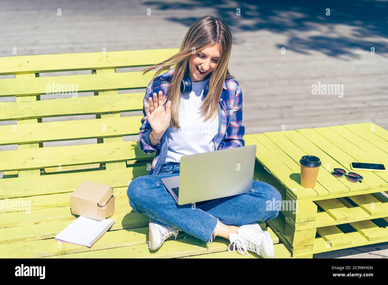 Woman with headphones having a facetime video call with laptop outside ...