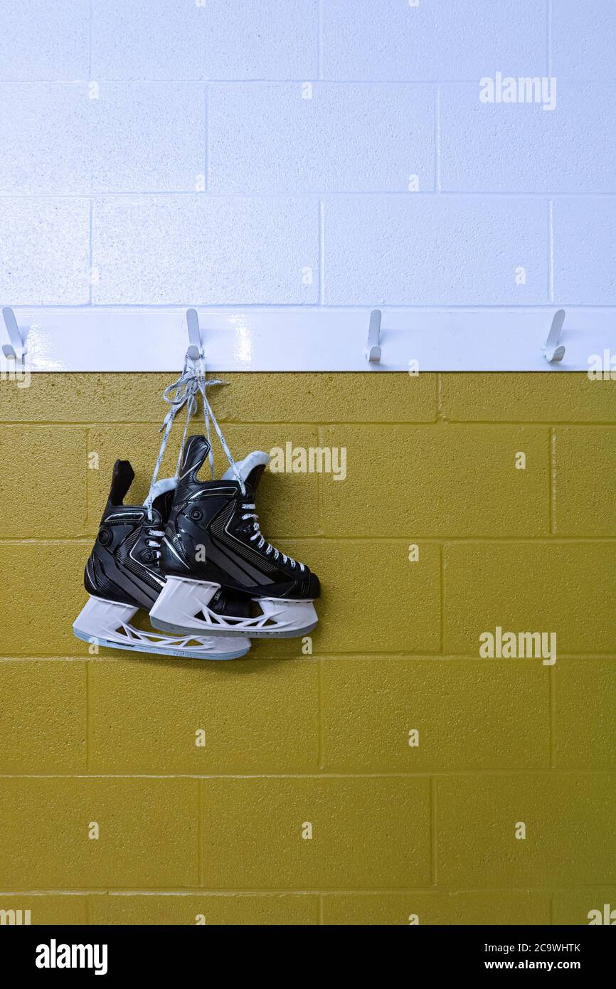 Hockey skate hanging in locker room over a yellow background with copy ...
