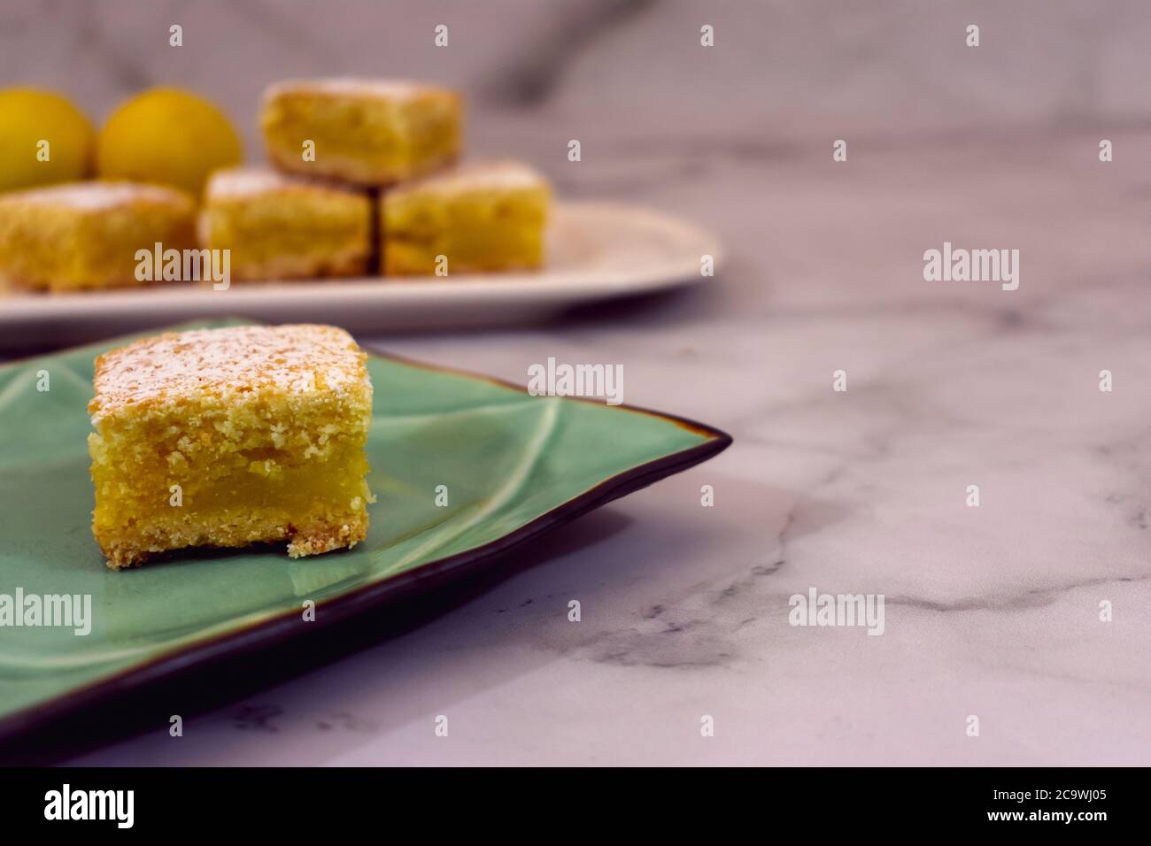Home-baked lemon squares, lemon bars, over minimal marble background ...