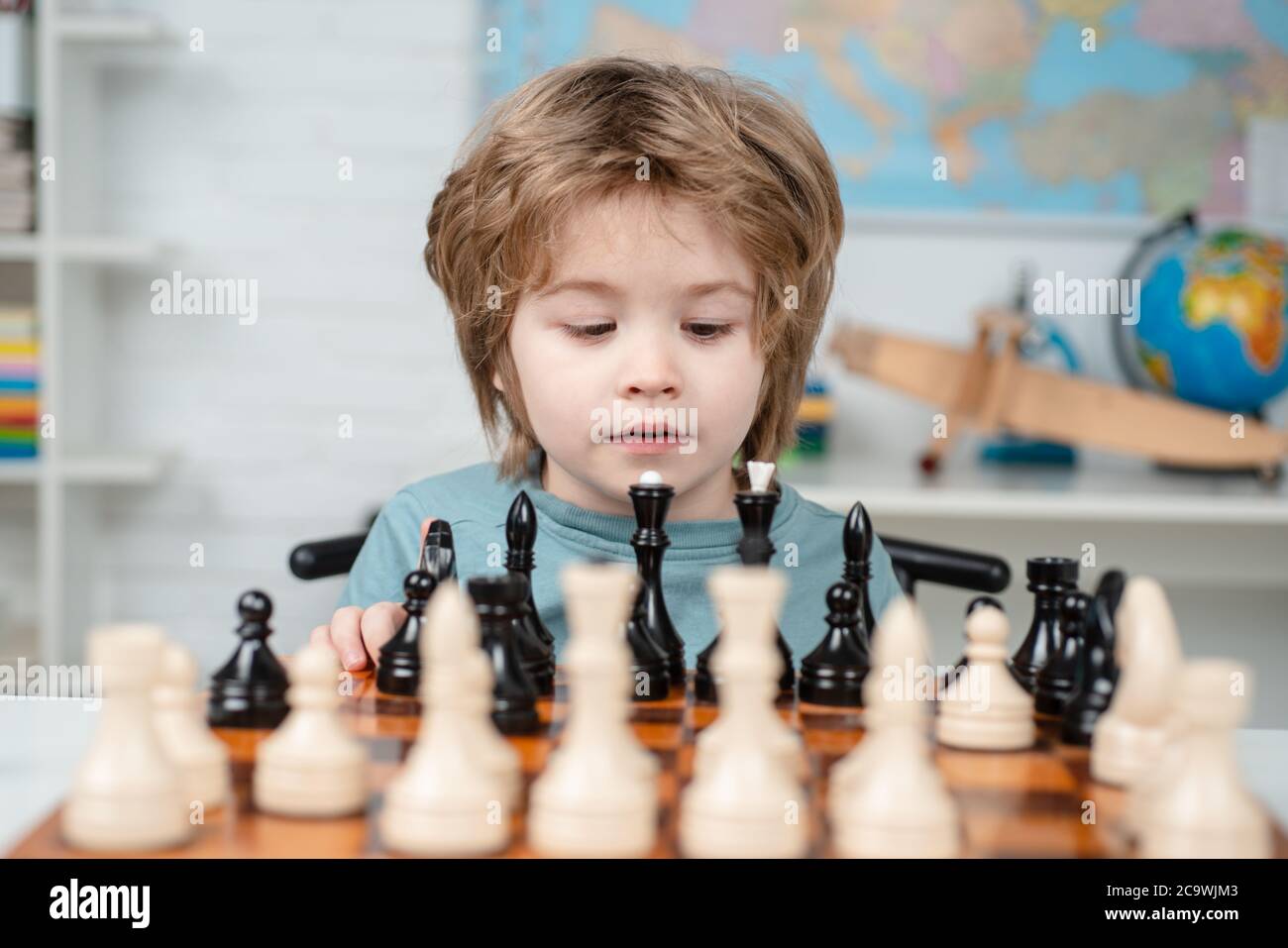 Pupil kid thinking about his next move in a game of chess. Kids early ...