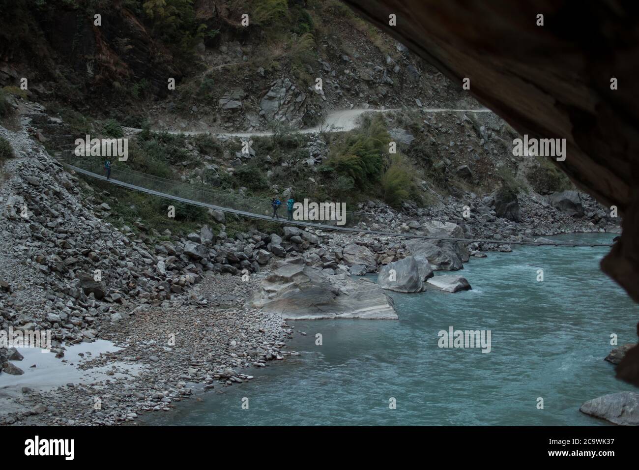 Three backpackers walking across a suspension bridge over the ...