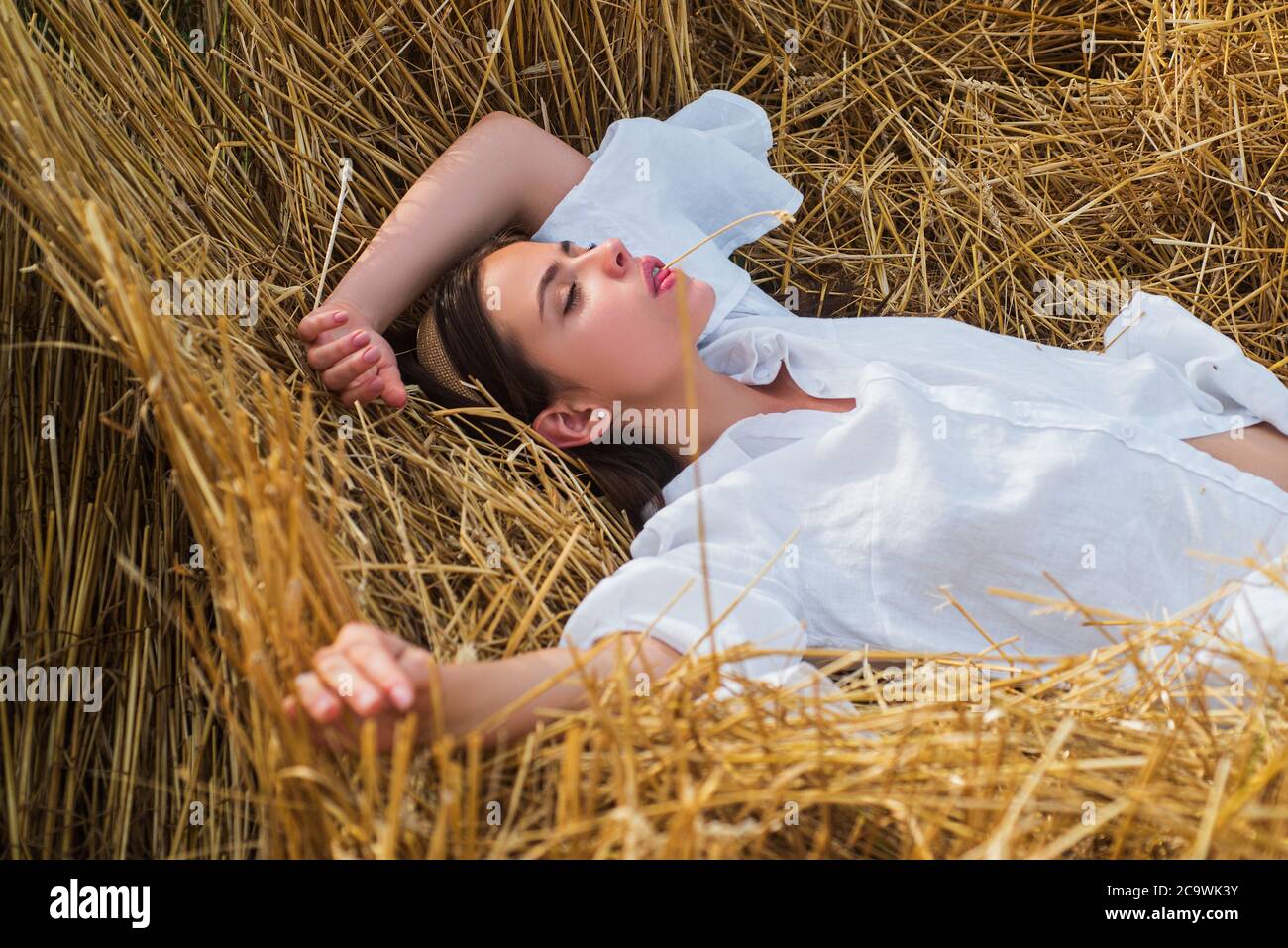 Sensual woman lying in the hay. Girl in white shirt and lies on a ...