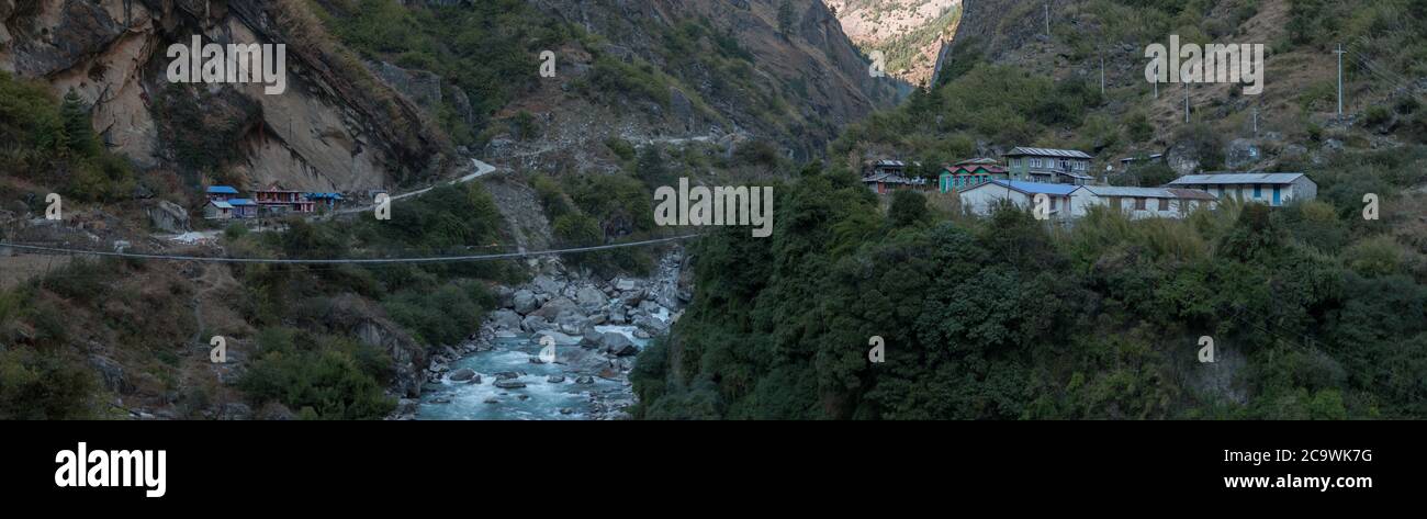 Panorama of nepalese mountain village by a suspension bridge over the ...