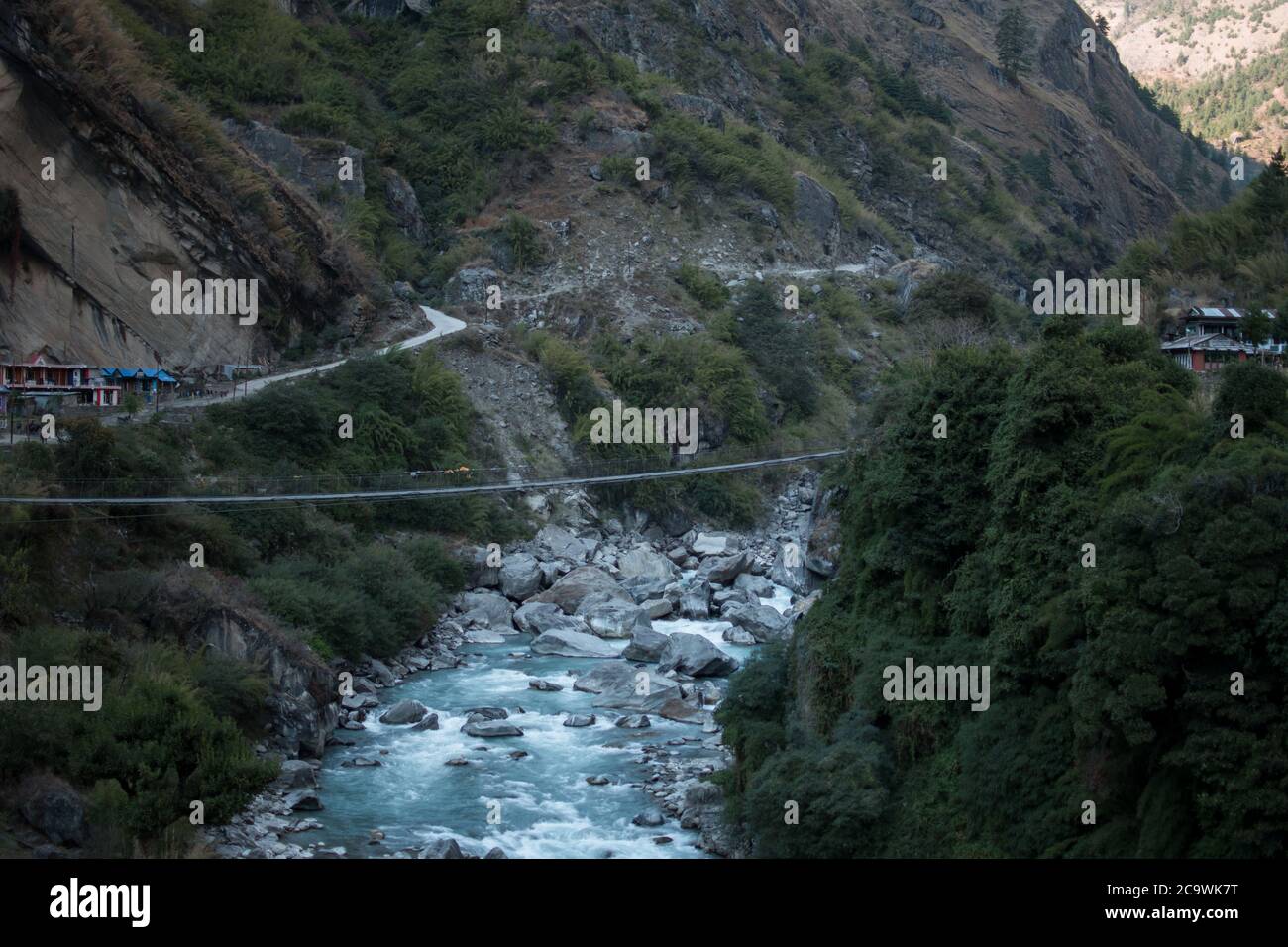 Nepalese mountain village by a suspension bridge over the Marshyangdi ...