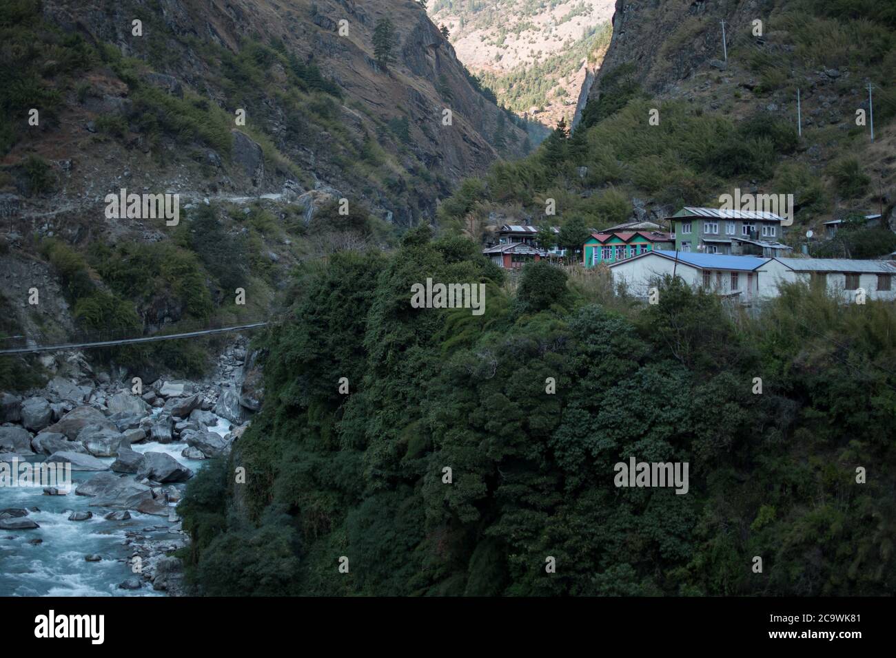 Nepalese mountain village by a suspension bridge over the Marshyangdi ...