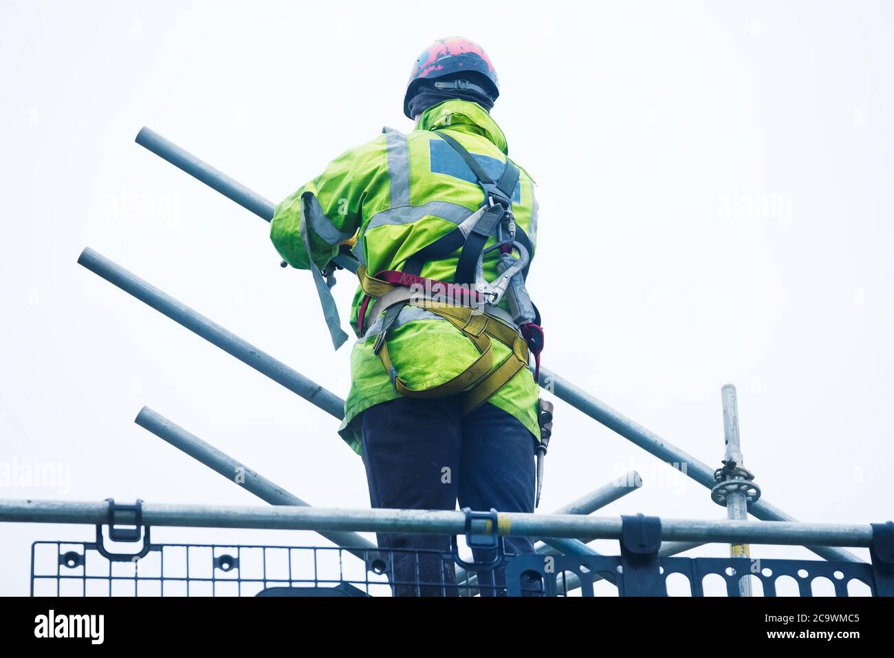 Scaffold worker dismantling access structure on construction building ...