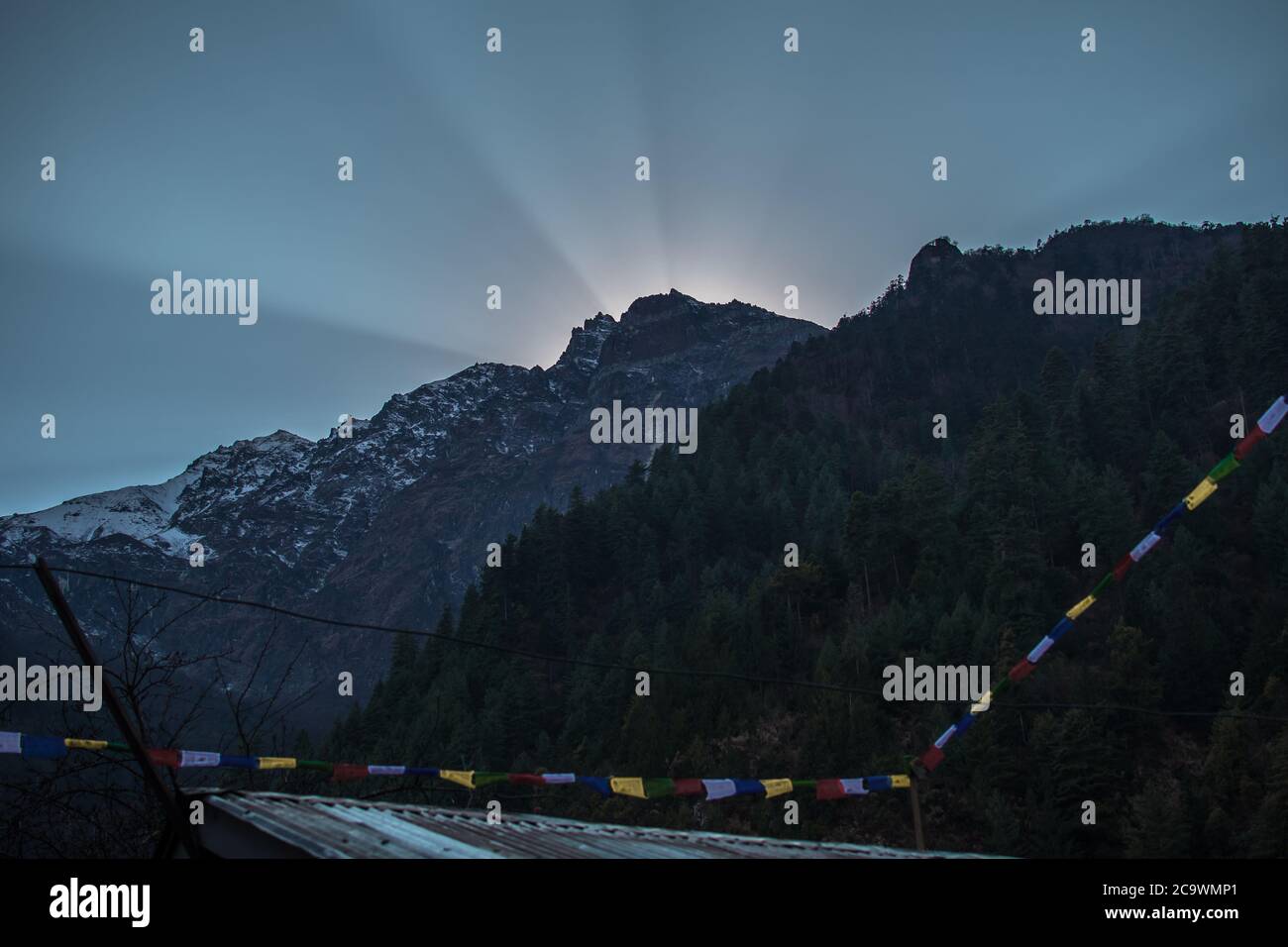 Bright sun rays peaking over the nepalese mountain tops over buddhist ...