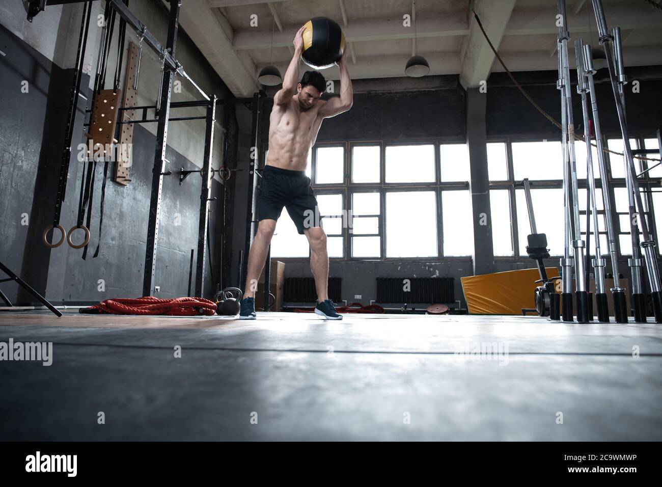 Fit man throwing medicine ball doing ball slam against gym floor or ...