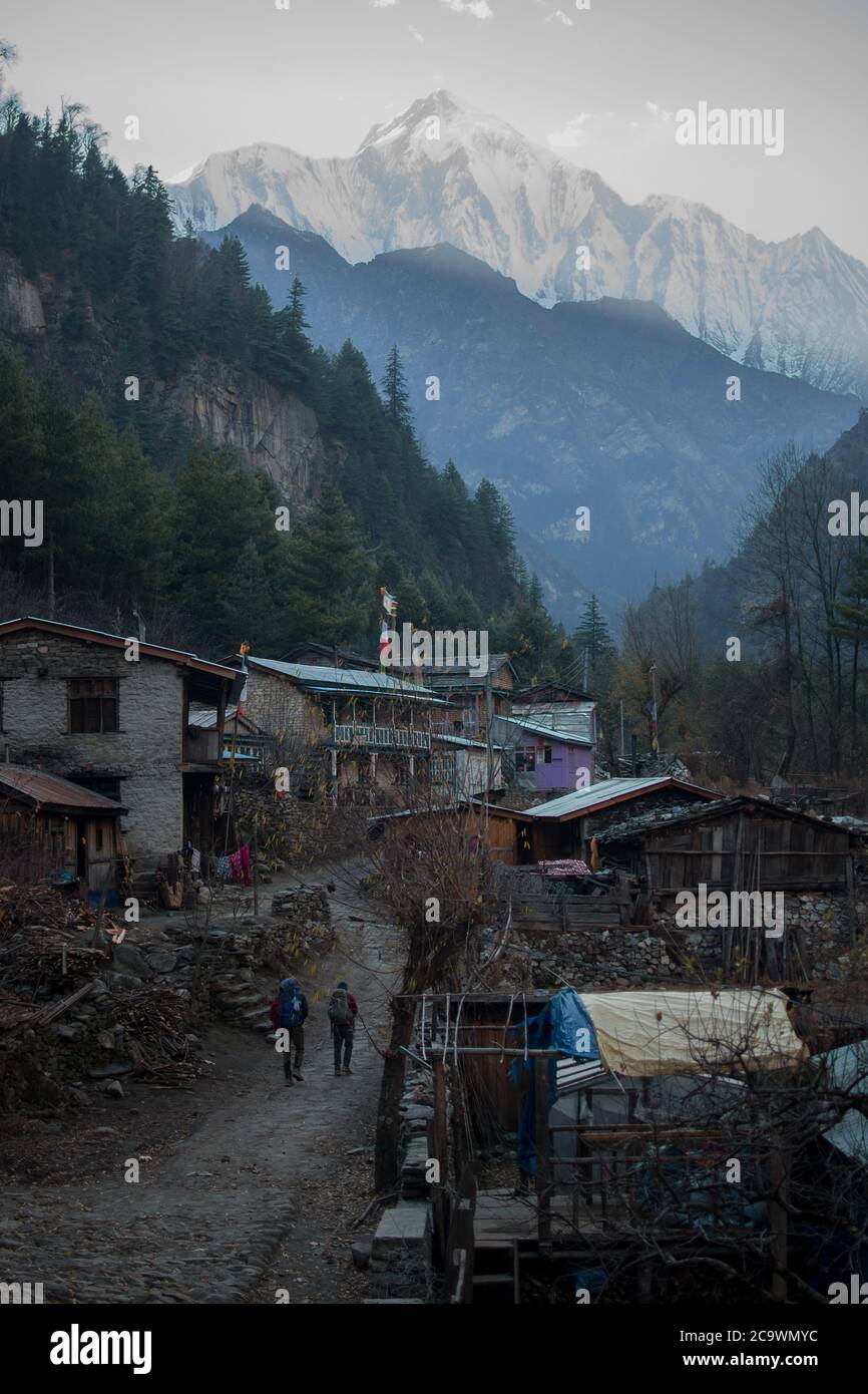 Two hikers trekking through nepalese mountain village, Annapurna ...