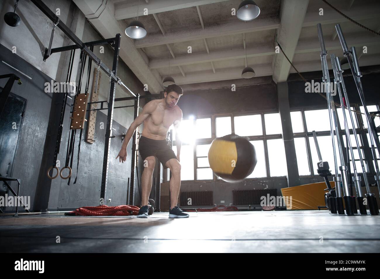 Fit man throwing medicine ball doing ball slam against gym floor or ...